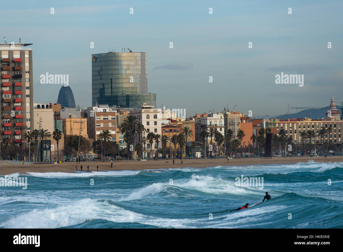 Surfers on waves with Barcelona skyline to the rear. Catalonia, Spain ...