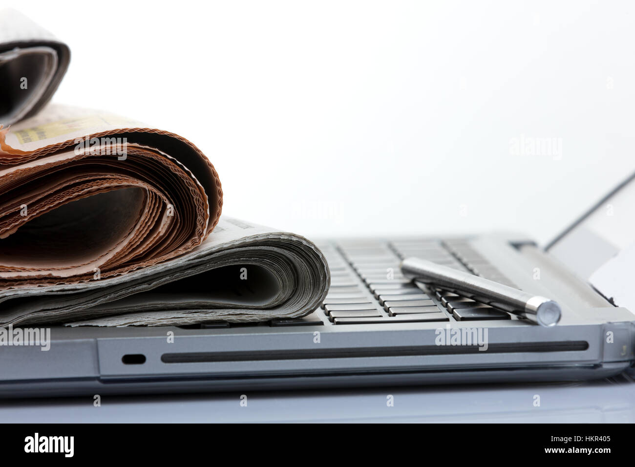 newspapers on a keyboard laptop and a pencil, white background with ...