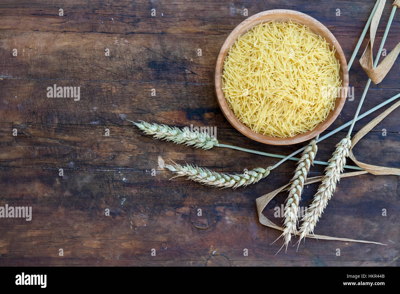 Uncooked Italian pasta Capellini in wooden pot with wheat ears on dark ...