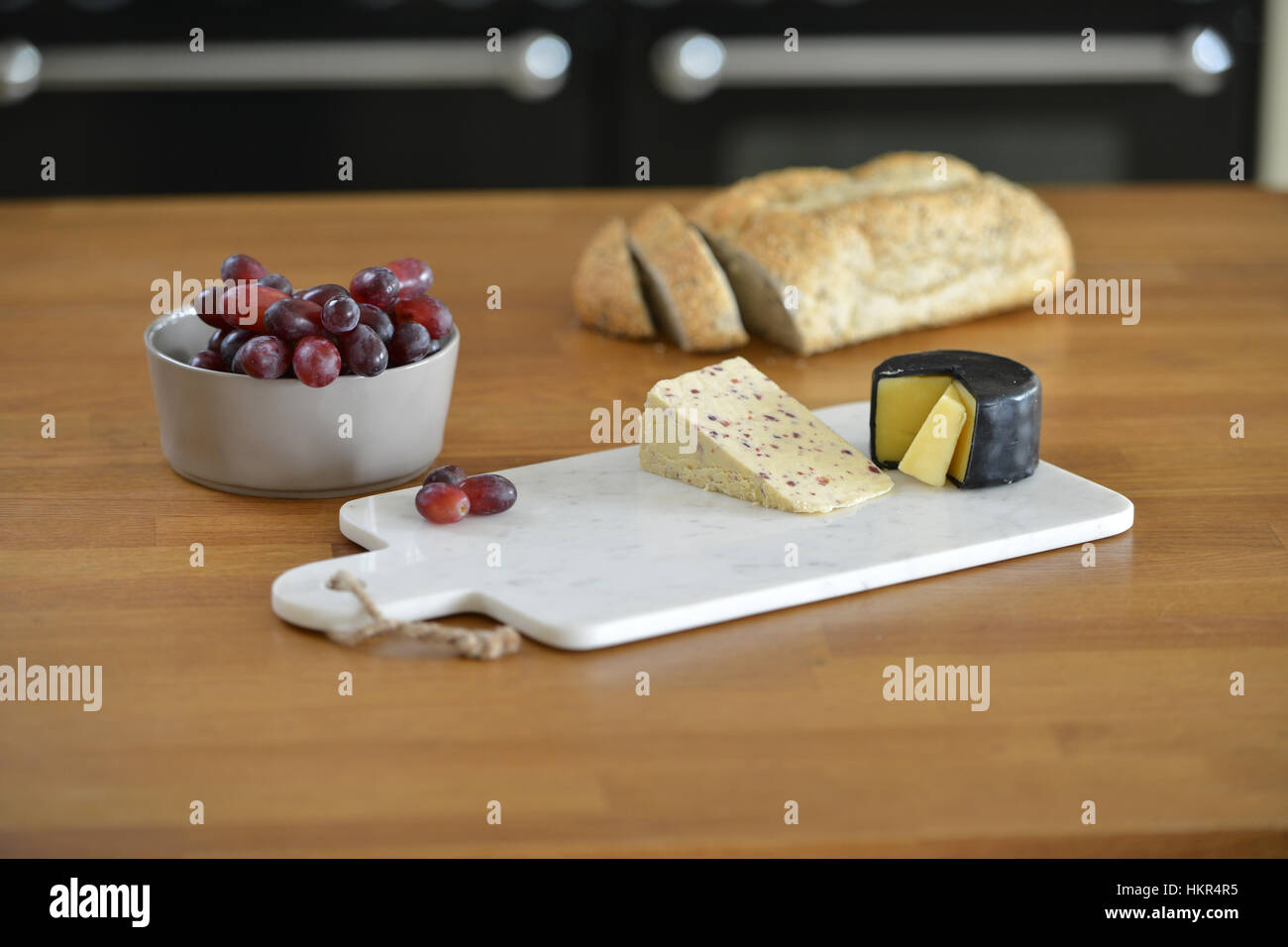 White marble cheese board in a kitchen with cheese and grapes Stock ...