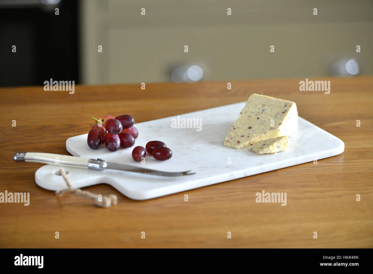 White marble cheese board in a kitchen with cheese and grapes Stock ...