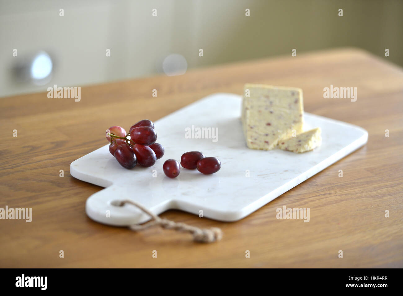 White marble cheese board in a kitchen with cheese and grapes Stock ...