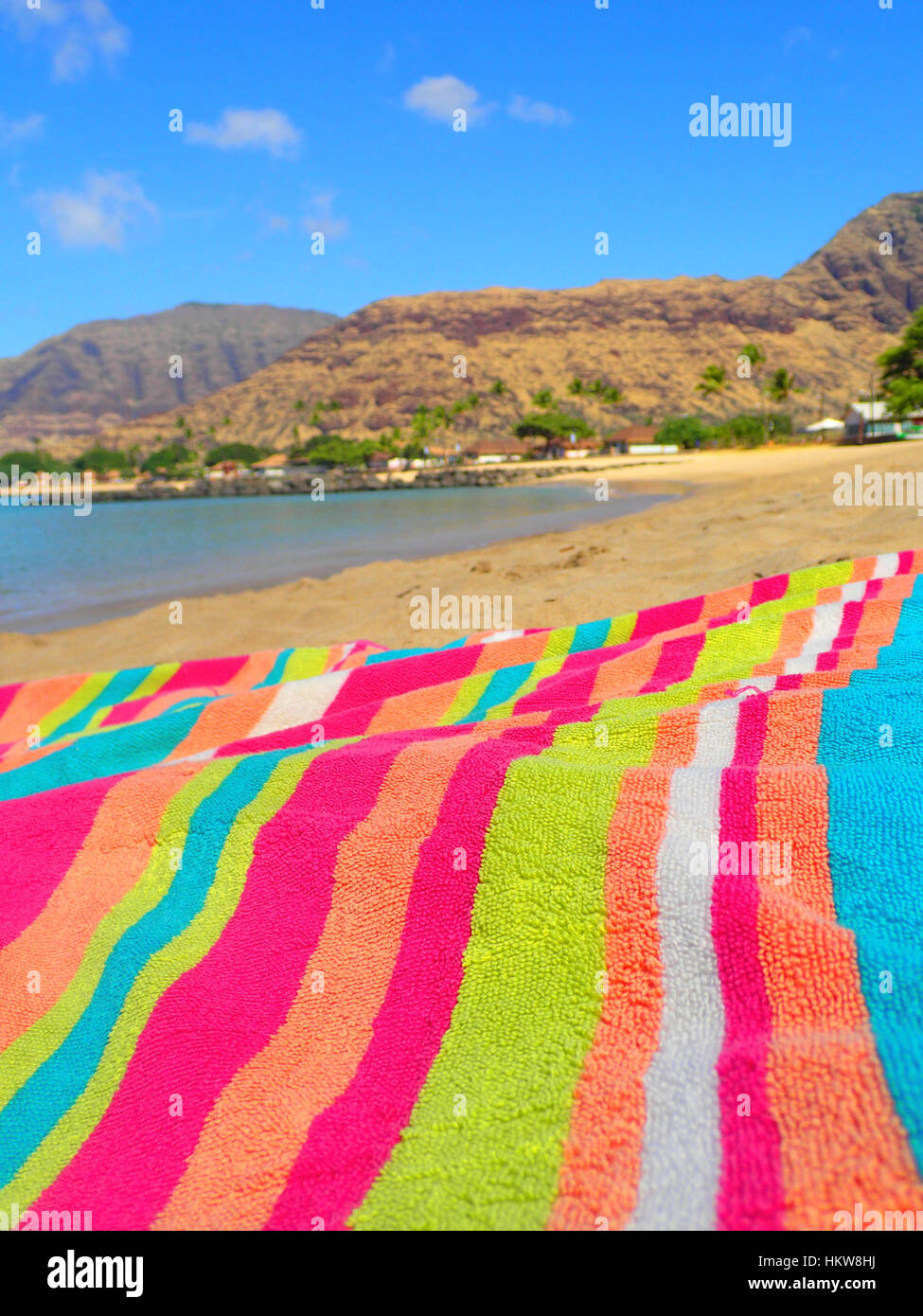 A brightly colored striped beach towel laying out on a beach at Pokai ...