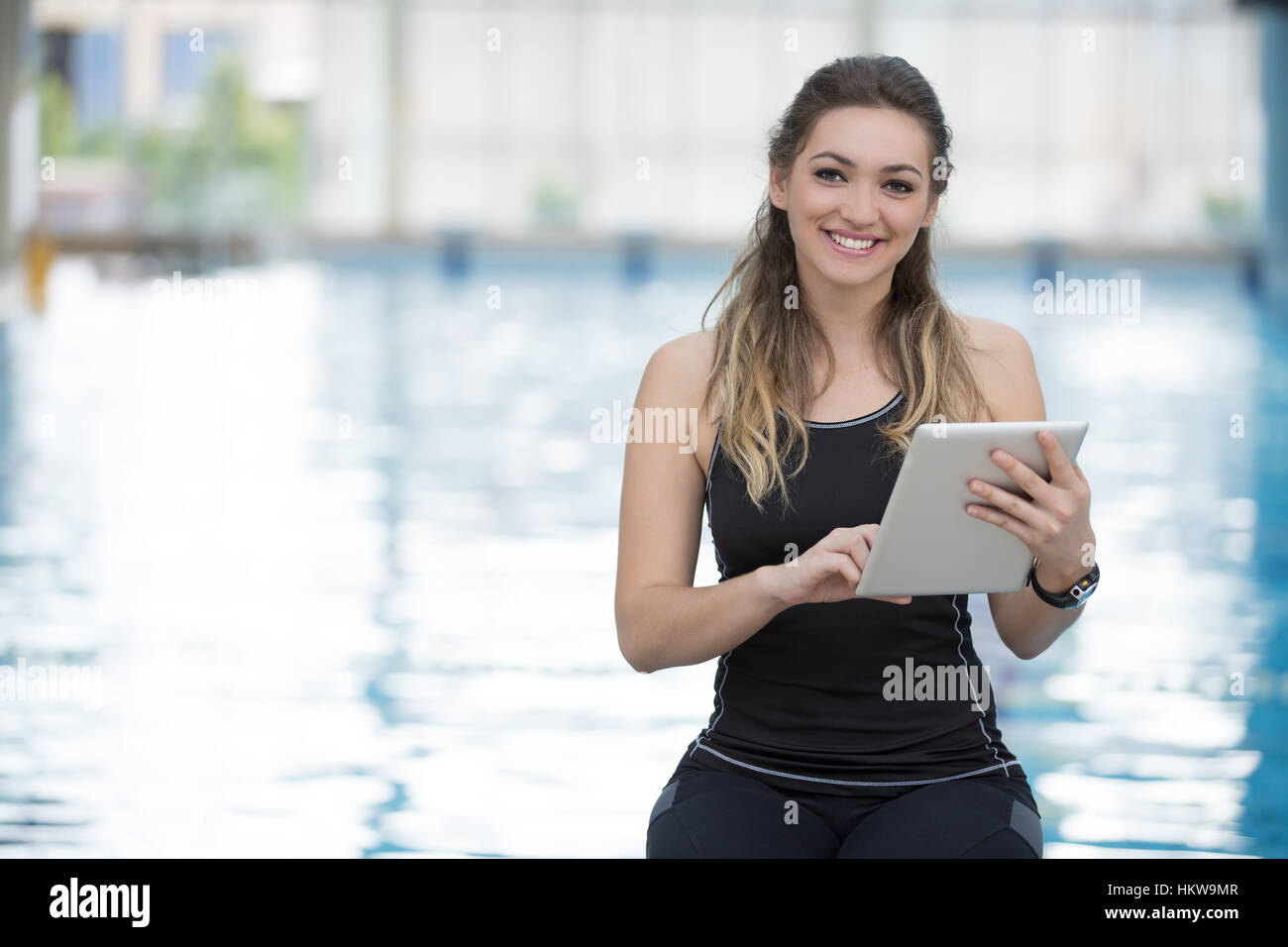 Fit female swimming trainer with tablet at the pool Stock Photo - Alamy