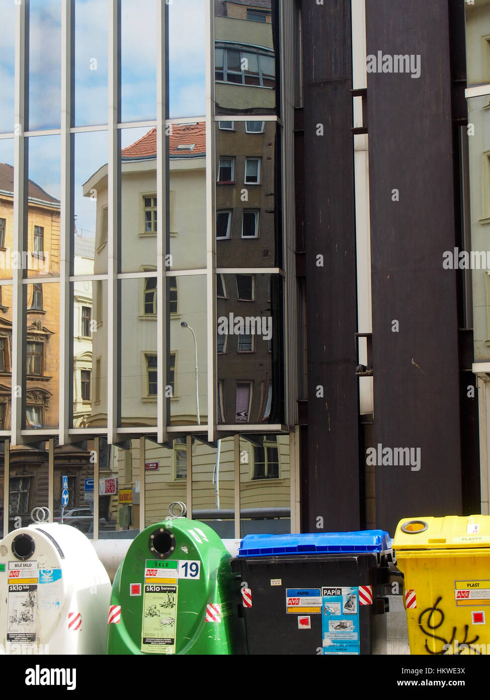 Urban scene of trash and recycling bins with city reflection in ...