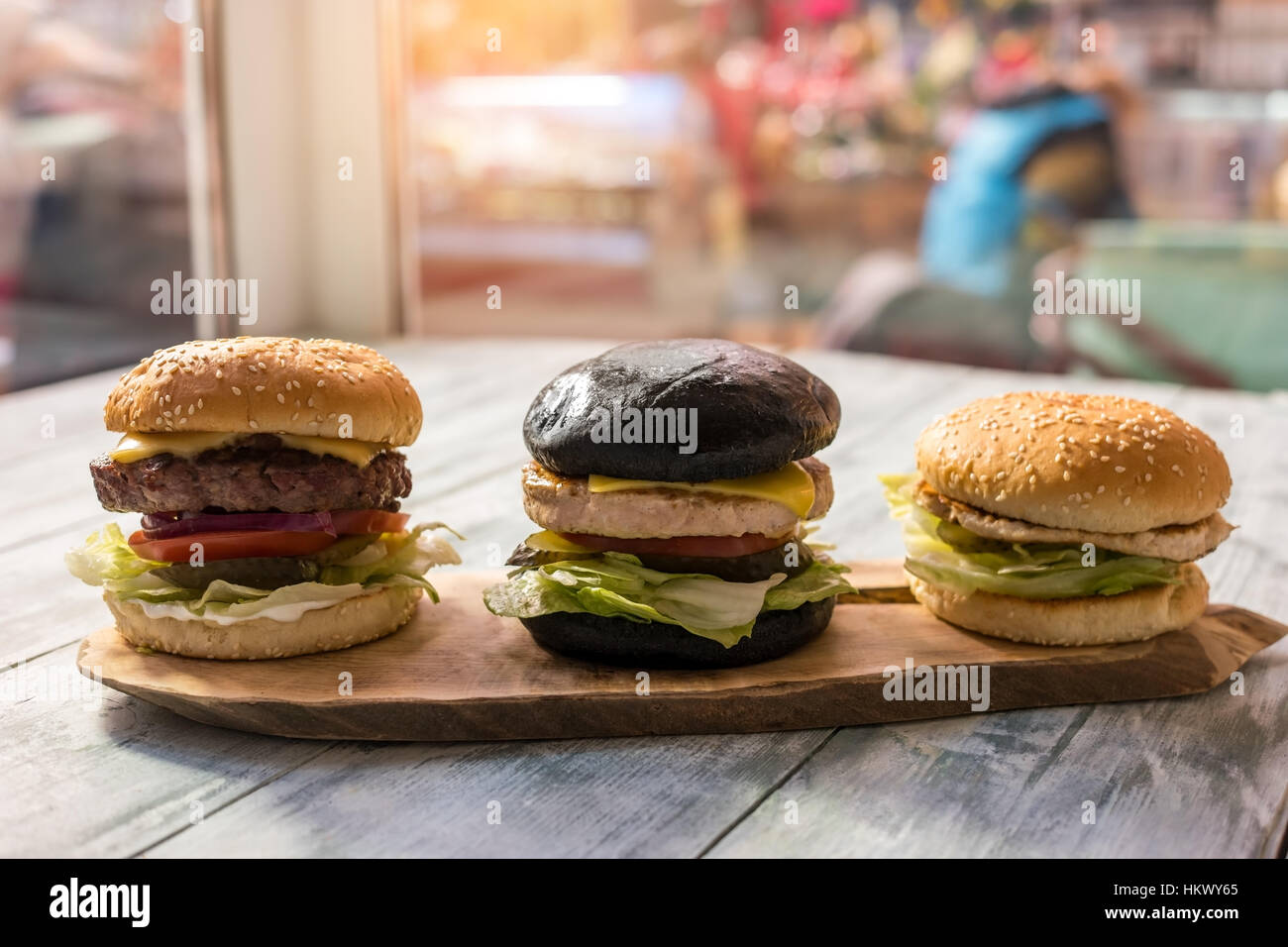 Three burgers on wood board Stock Photo - Alamy