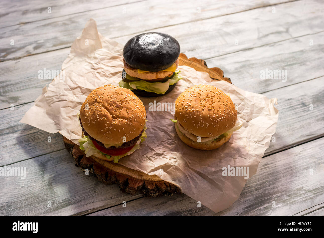 Three burgers on wooden background Stock Photo - Alamy