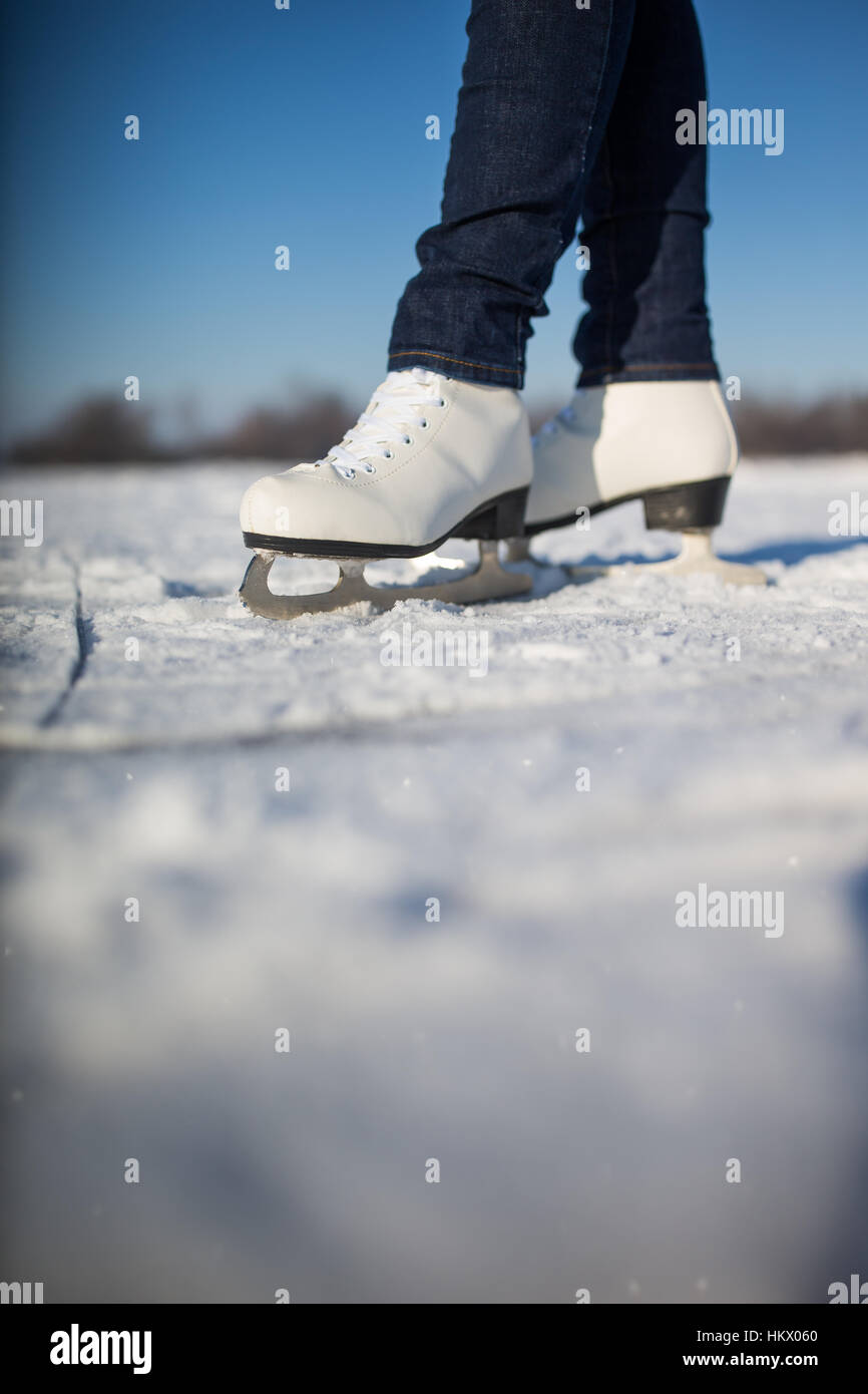 Young woman ice skating outdoors on a pond on a freezing winter day ...