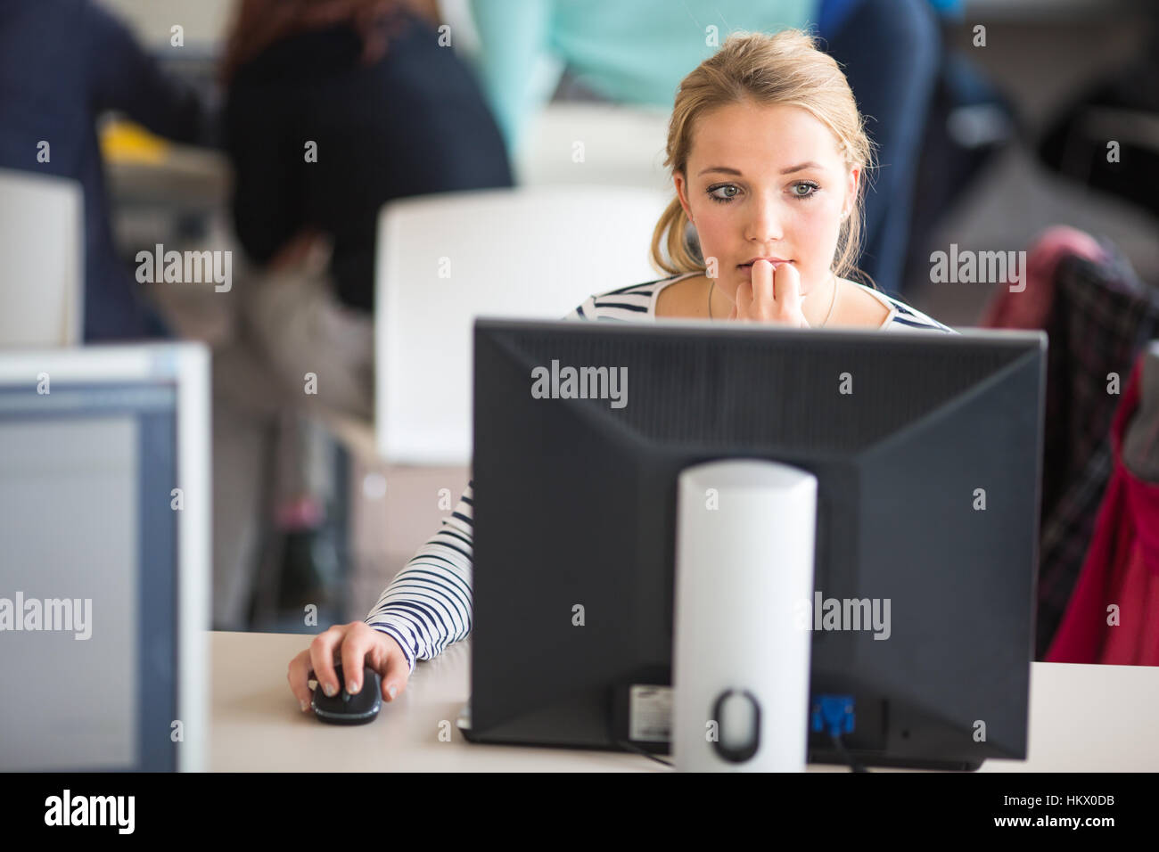 Pretty, female student looking at a desktop computer screen, learning ...