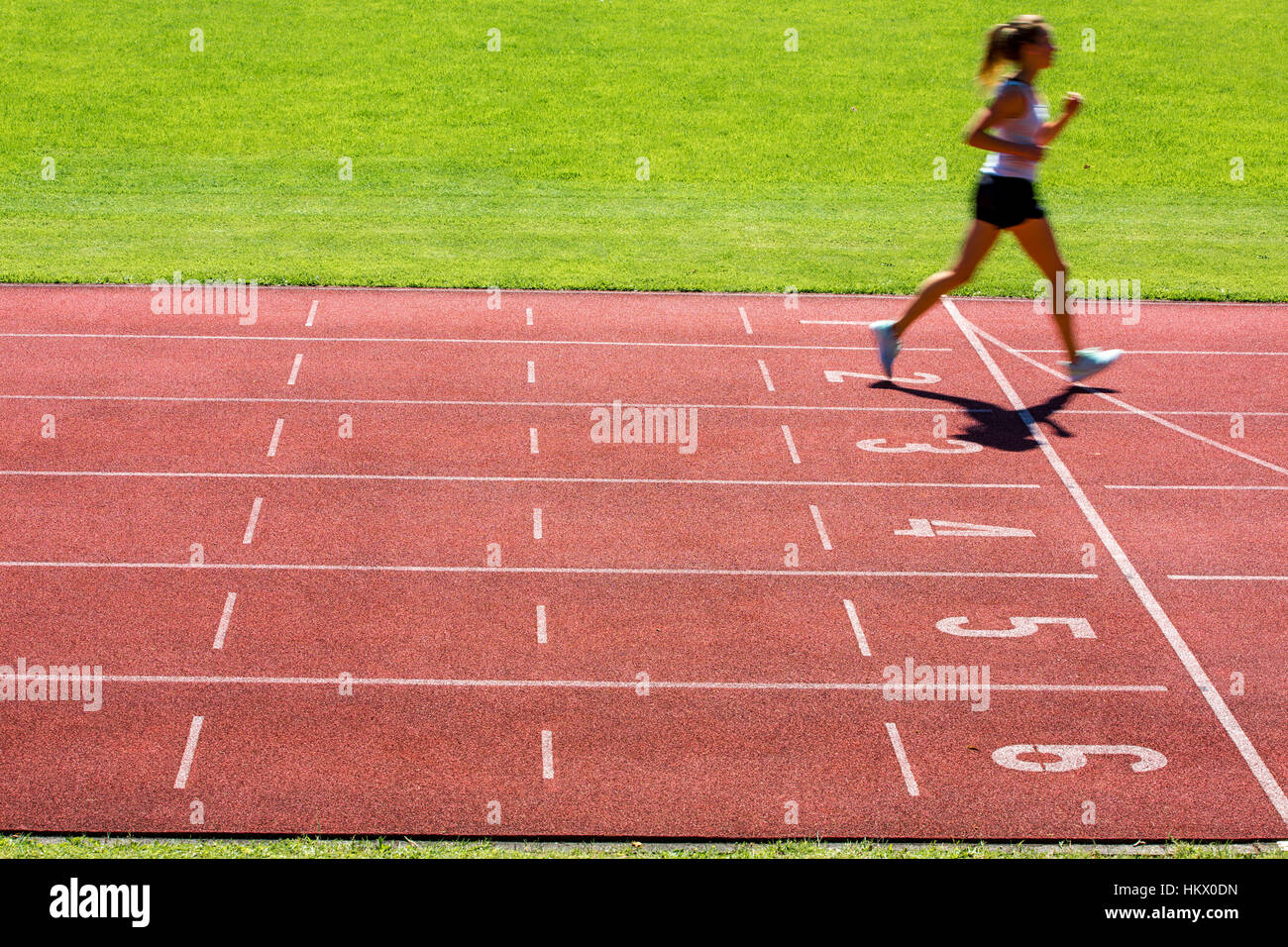 Runner on a running track finishing a race first (motion blurred image ...