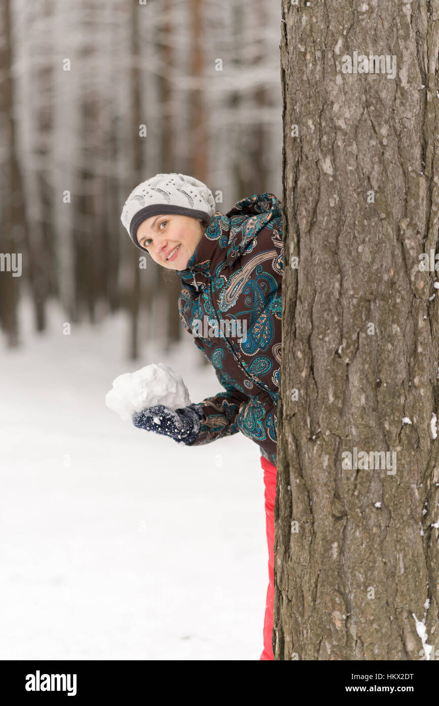 Beautiful smiling girl playing in the snow and preparing to ambush ...