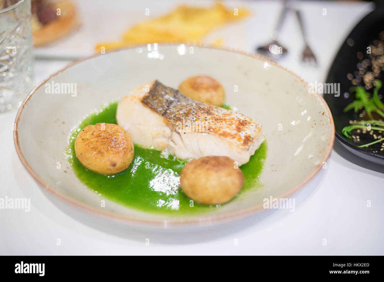elegant rustic circular bowl plate with hake fish cooked with green ...
