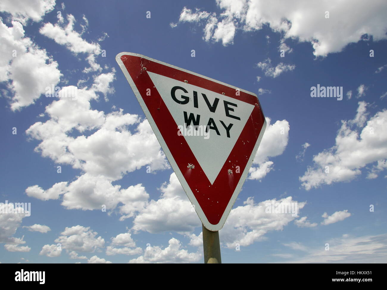 Give way traffic sign in front of blue sky with white clouds Stock ...