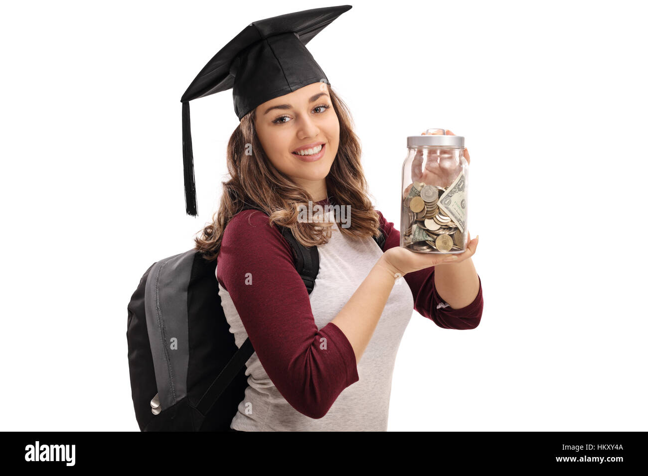 Cheerful graduate student holding a jar filled with money isolated on ...