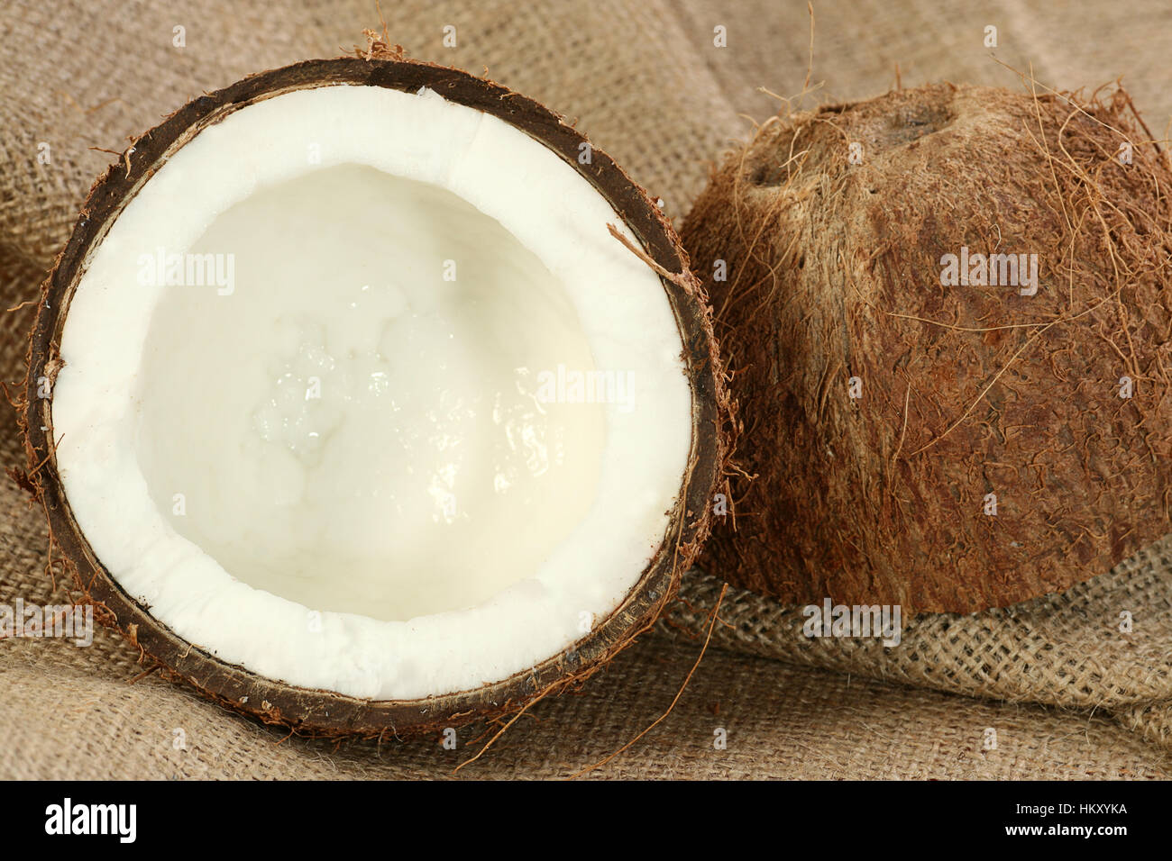 fresh coconut cut in half on a hessian background Stock Photo - Alamy