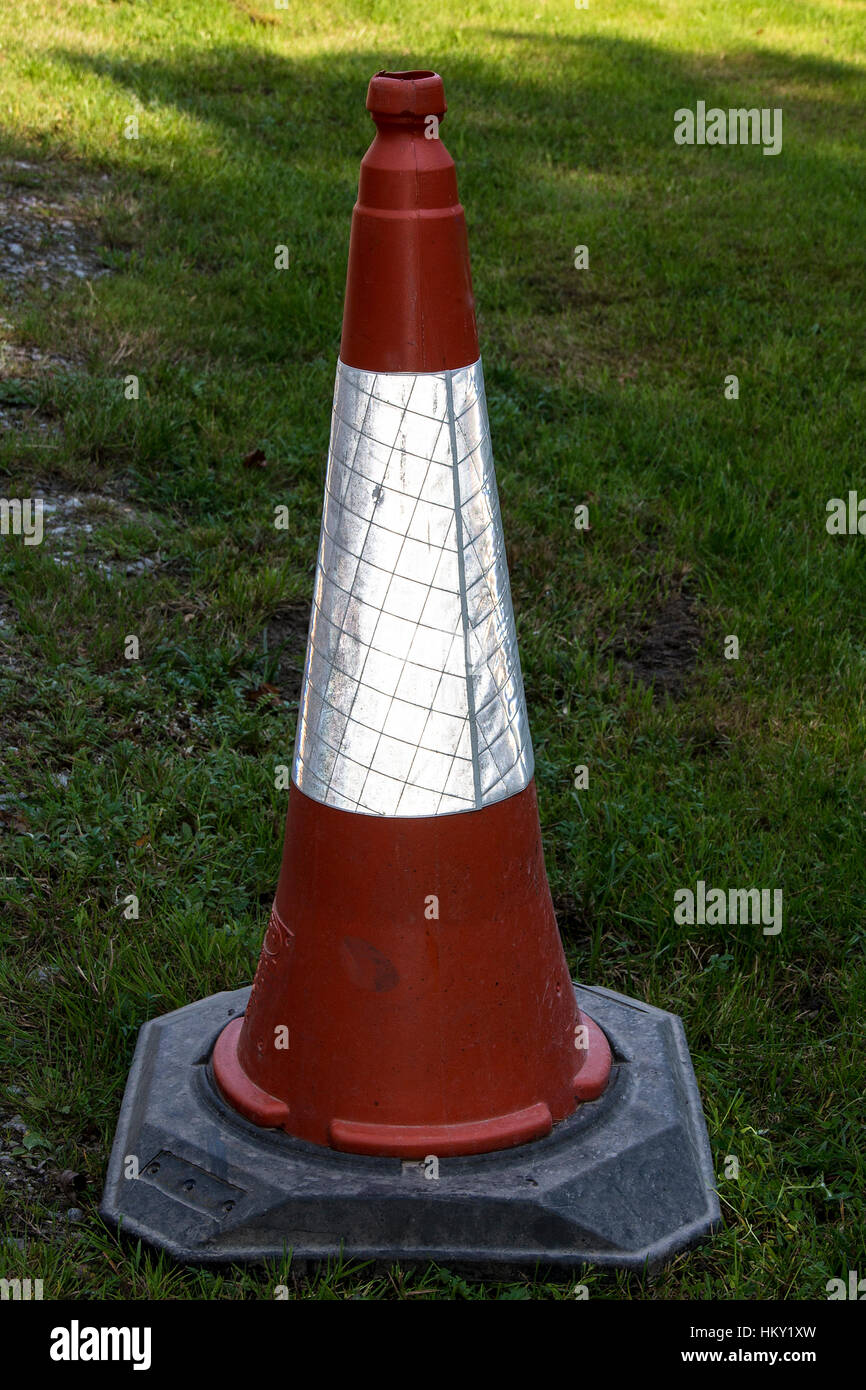 Single red traffic cone with reflective band on grass Stock Photo - Alamy