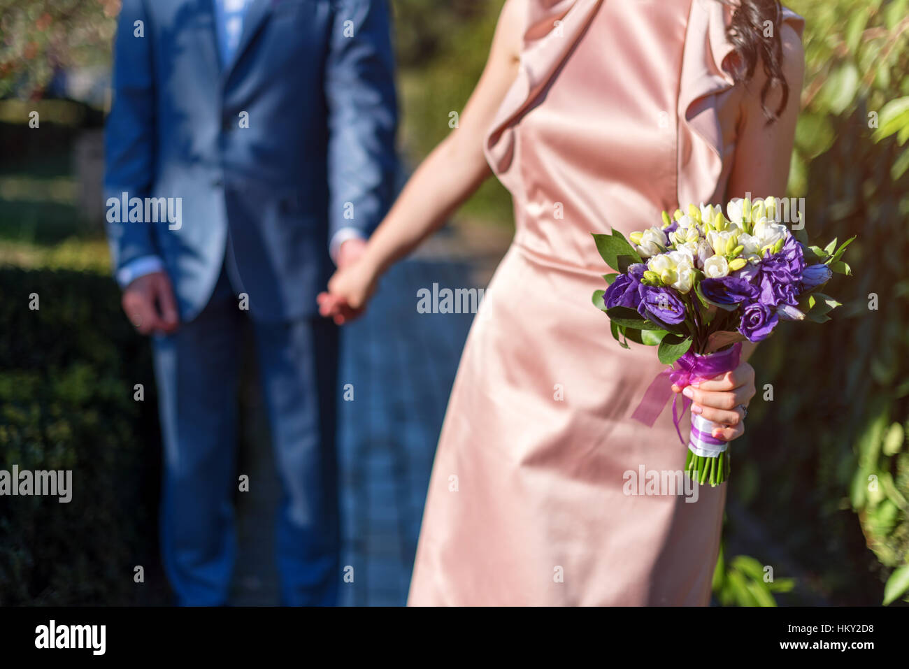Wedding couple with bouquet outdoors holding hands Stock Photo - Alamy