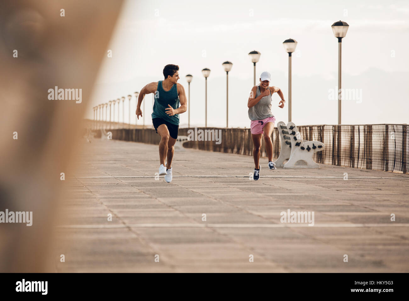 Two runner sprinting on road by the sea. Fitness couple running on the ...