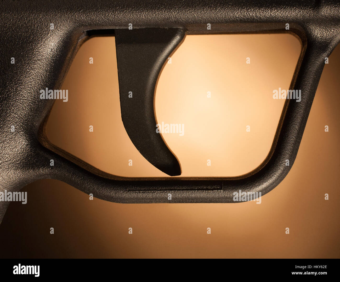 Trigger on an assault rifle with a dark tan background Stock Photo - Alamy