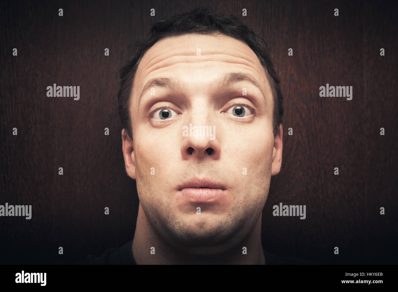 Young surprised Caucasian man. Close-up studio face portrait over dark ...