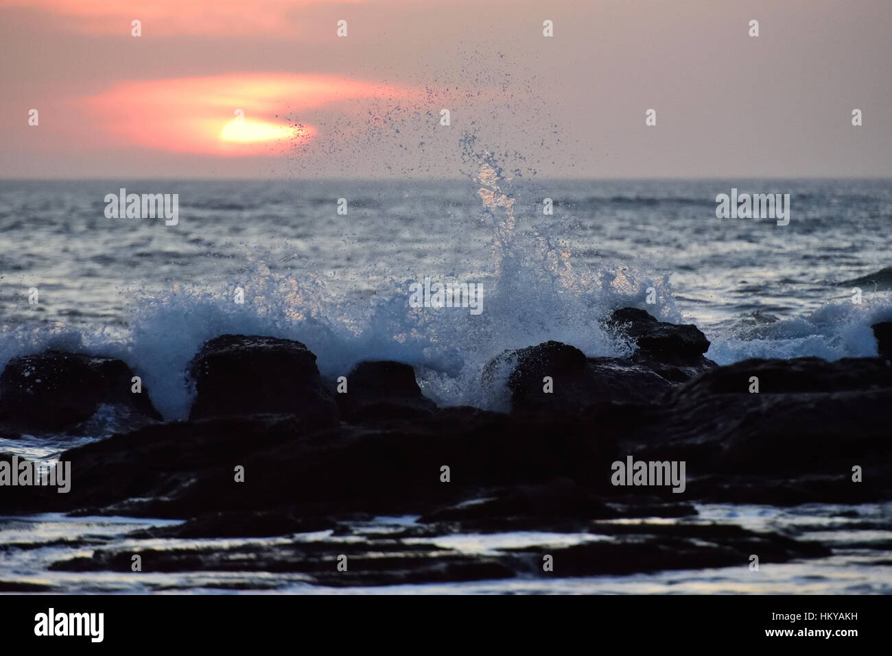 Splash of ocean water on rock during sunset Stock Photo - Alamy