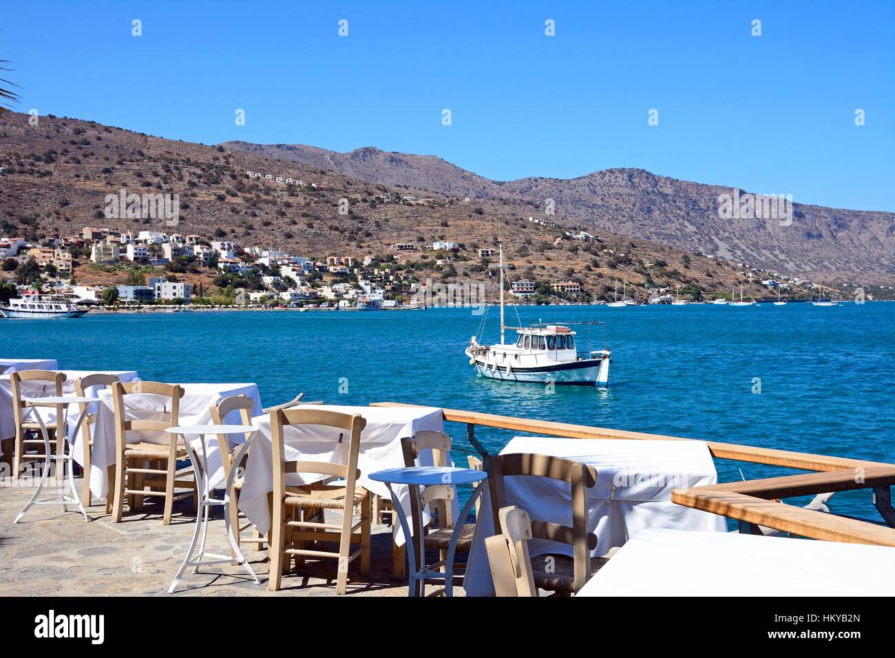 Restaurant tables on the waterfront with views across the bay, Elounda ...