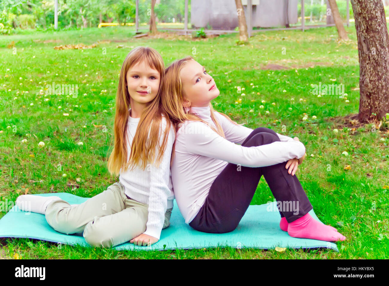 Photo of two girls sitting on grass in summer Stock Photo - Alamy
