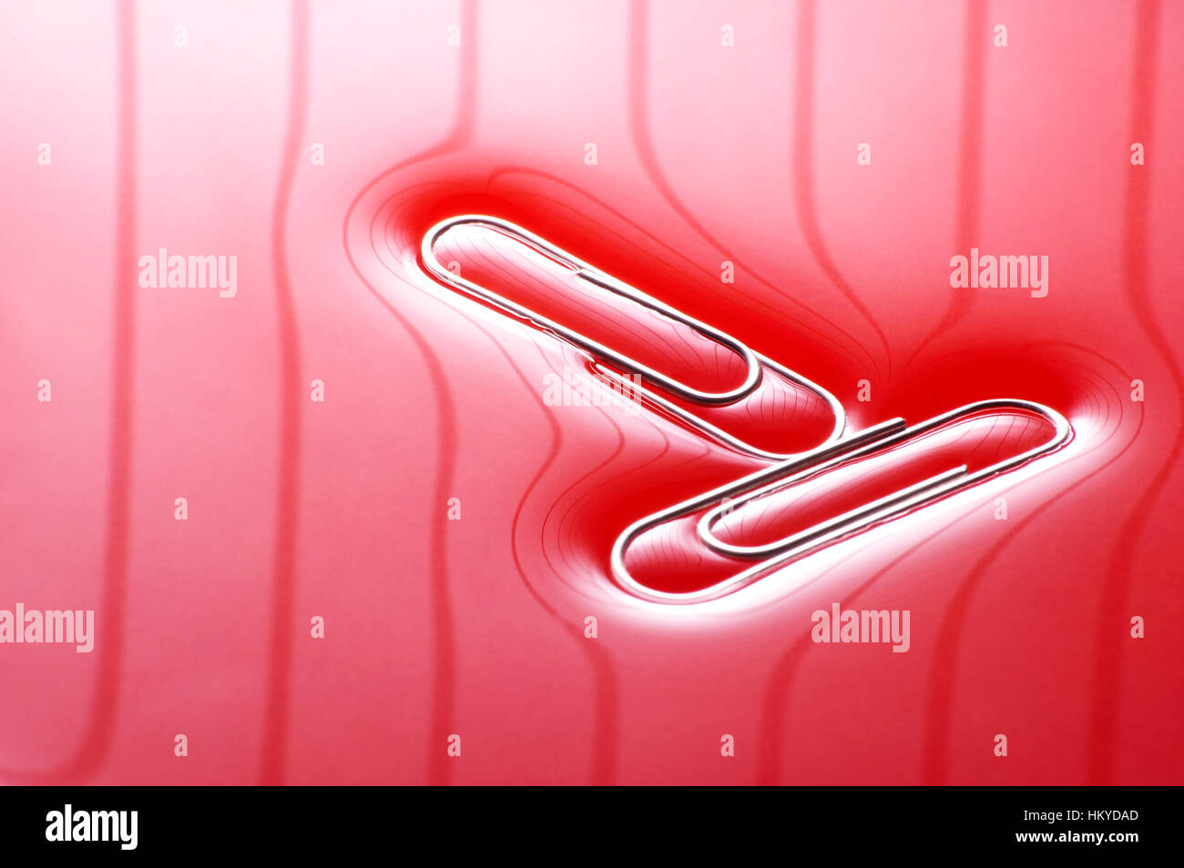 two office paper clips on red background Stock Photo - Alamy