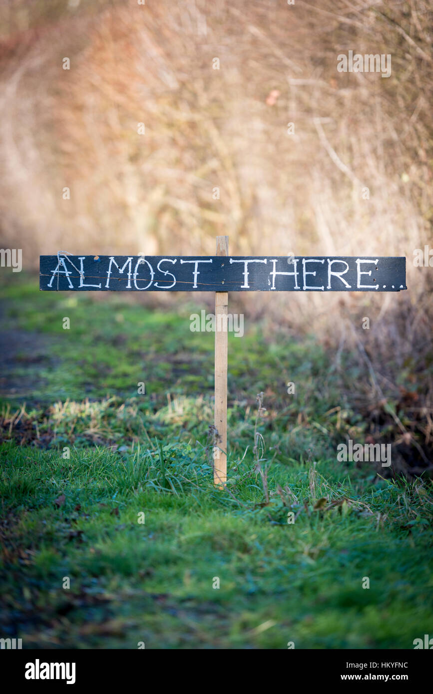 A homemade Almost There signpost giving directions to the end or ...