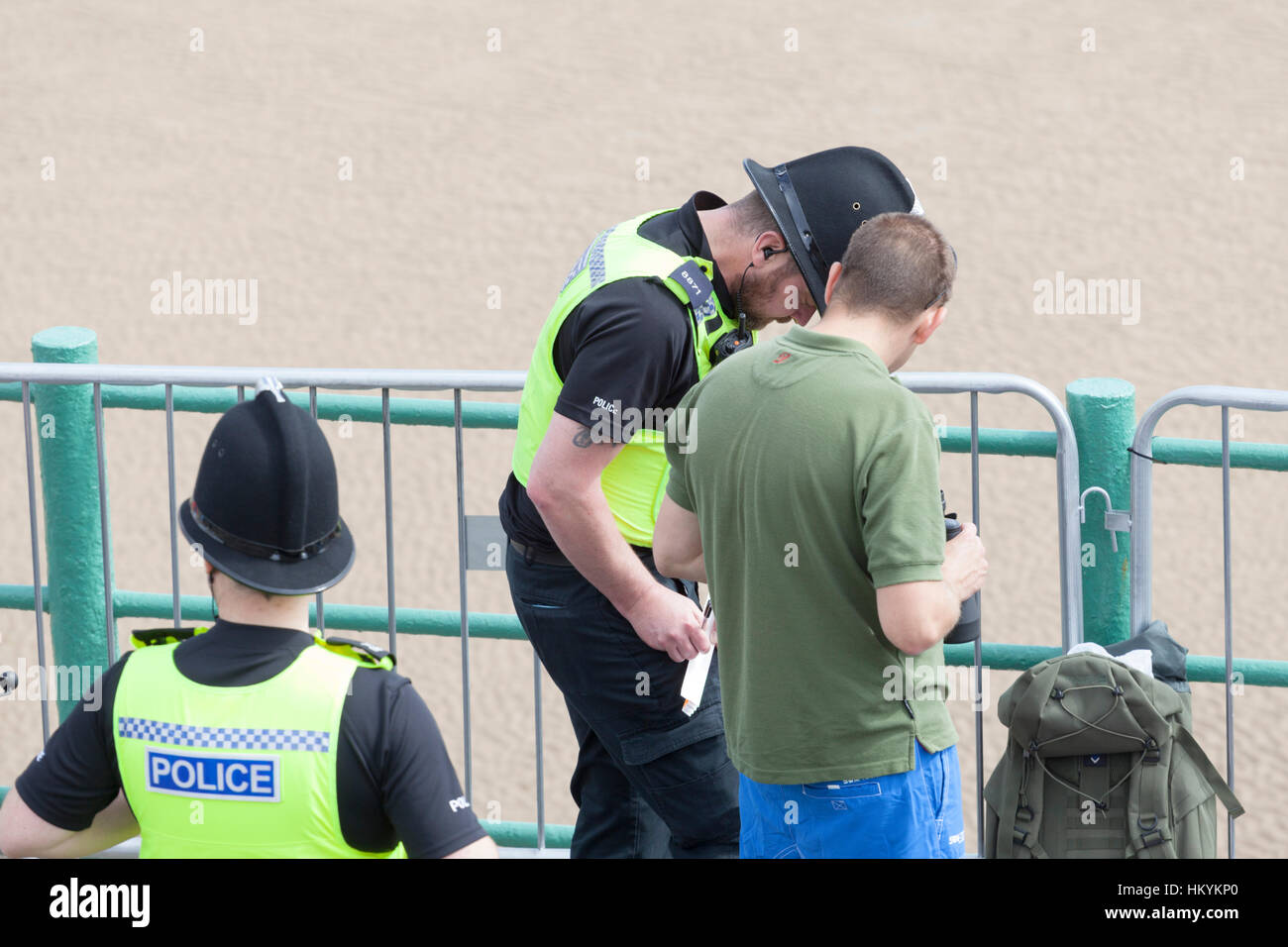 Two police officers questioning a man and writing a ticket the seafront ...