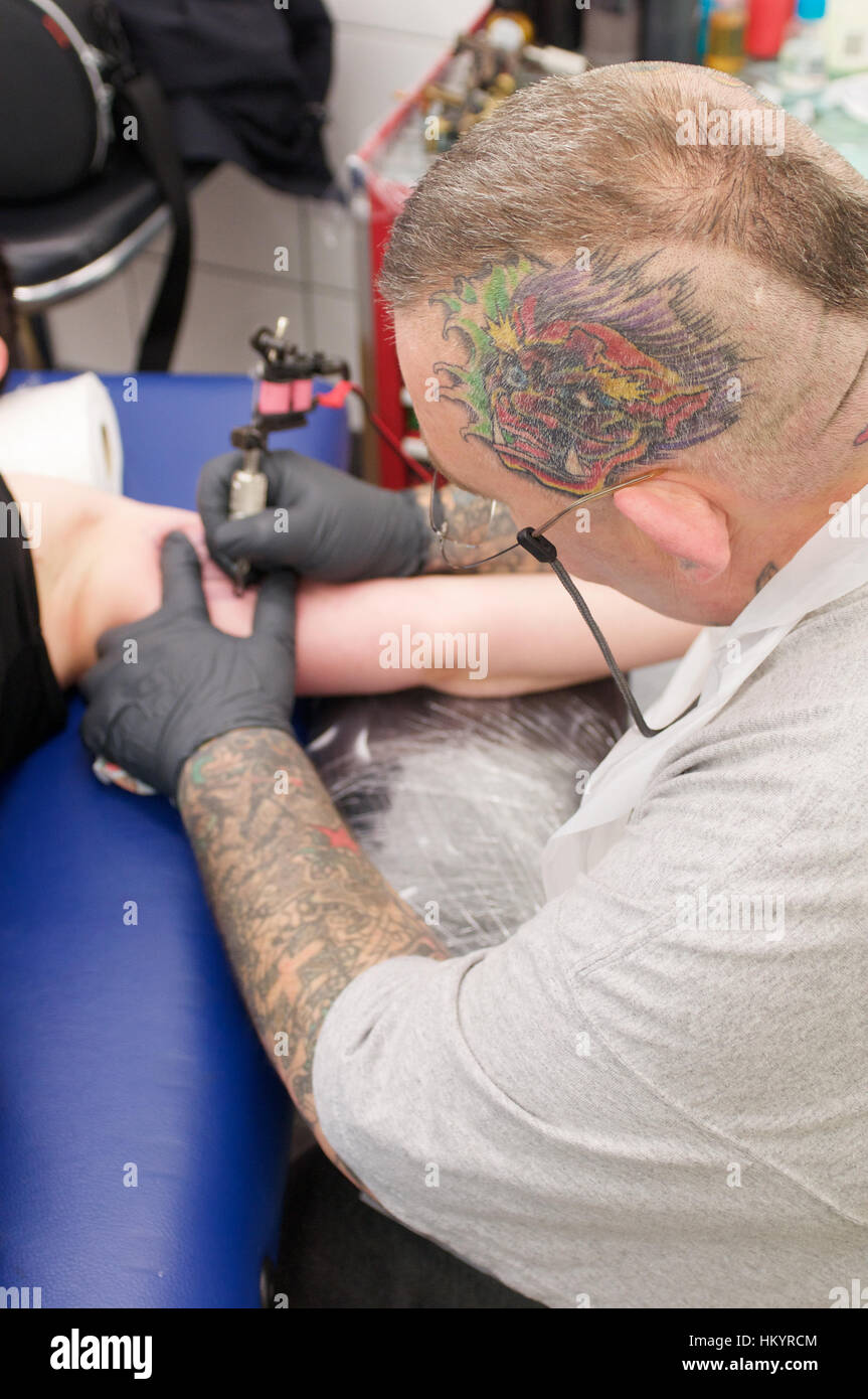 Tattoo artist at work in his studio on a client Stock Photo - Alamy