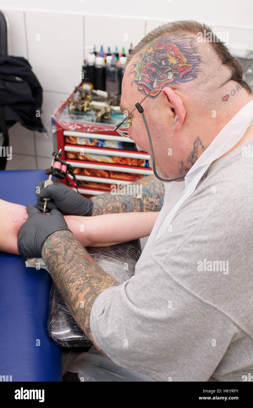 Tattoo artist at work in his studio on a client Stock Photo - Alamy
