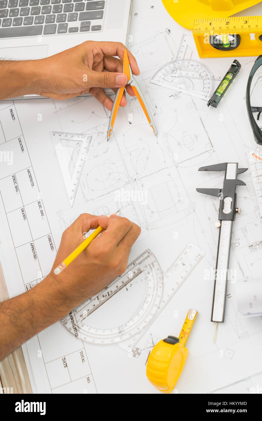 Hand over Construction plans with yellow helmet and drawing tools on ...