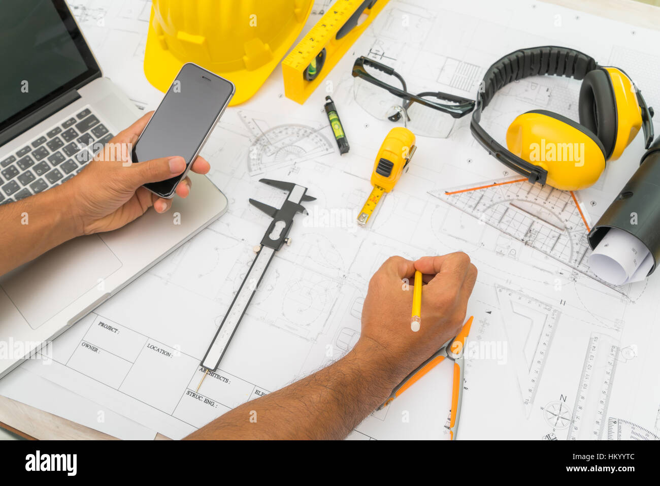 Hand over Construction plans with yellow helmet and drawing tools on ...
