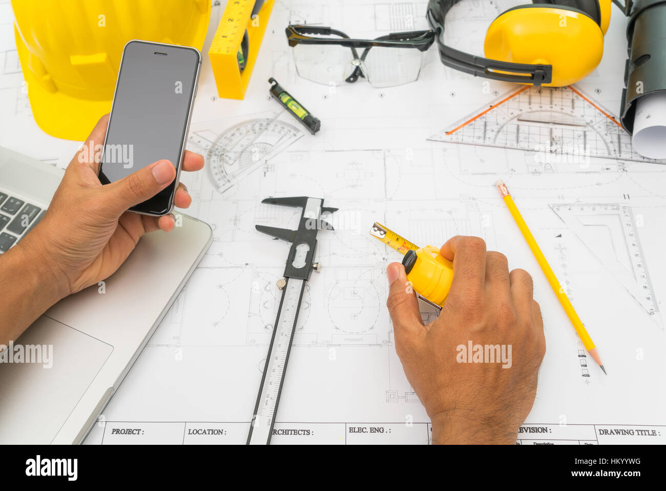 Hand over Construction plans with yellow helmet and drawing tools on ...