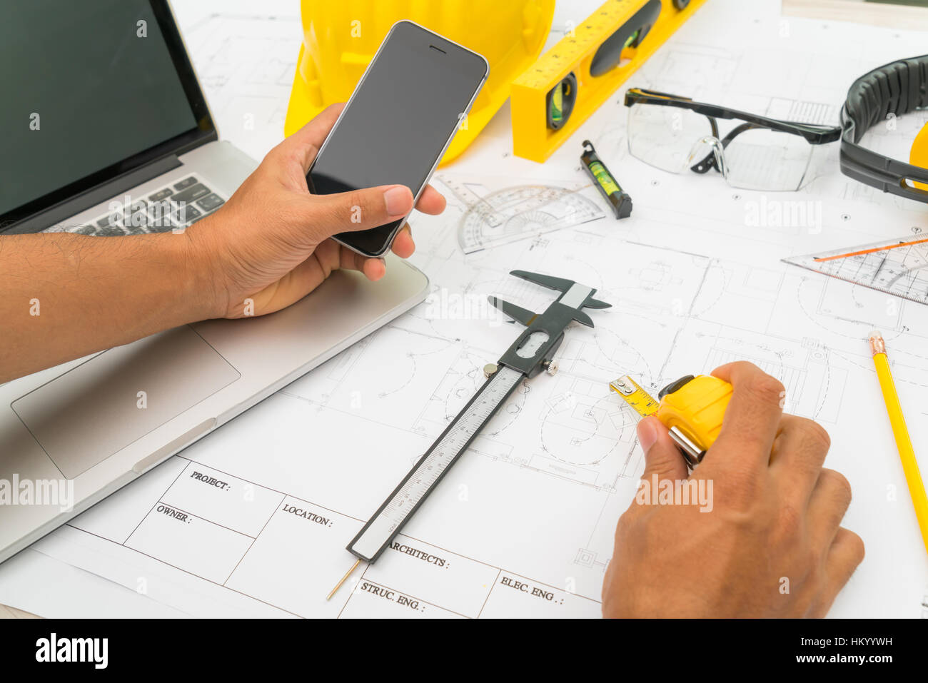 Hand over Construction plans with yellow helmet and drawing tools on ...