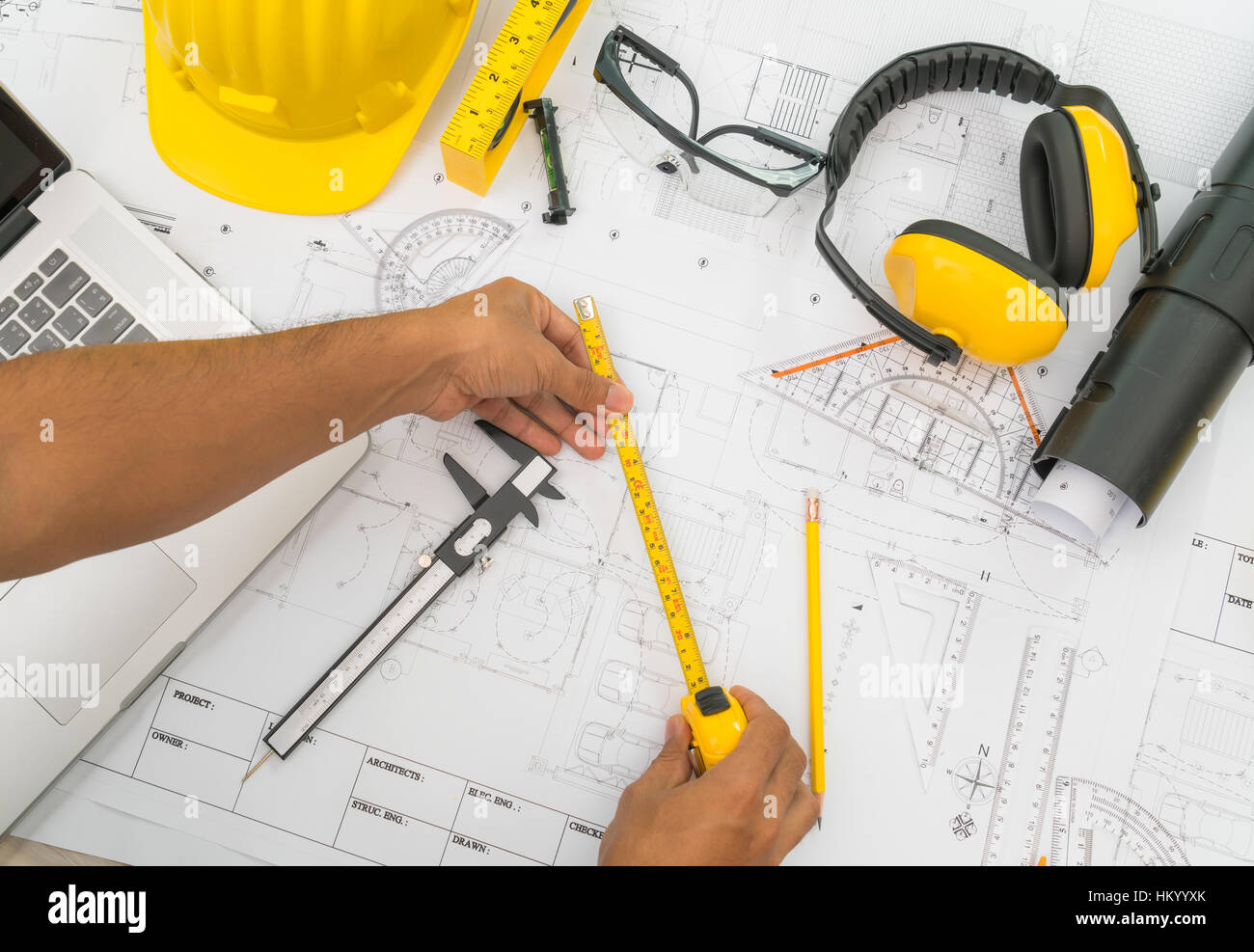 Hand over Construction plans with yellow helmet and drawing tools on ...