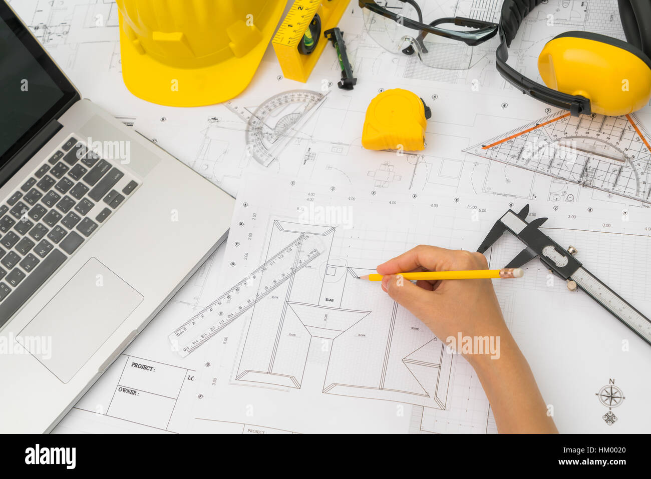Hand over Construction plans with yellow helmet and drawing tools on ...