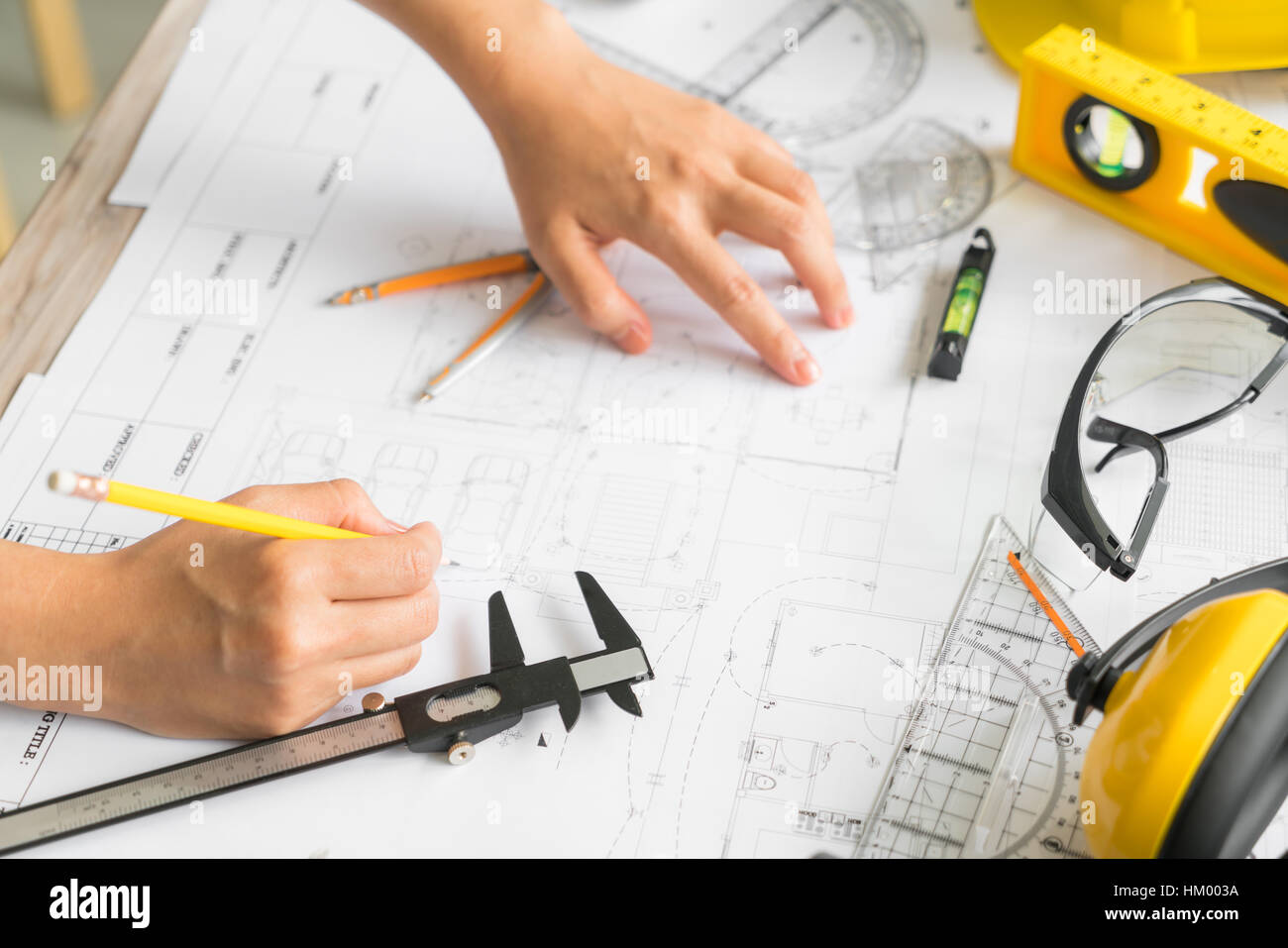 Hand over Construction plans with yellow helmet and drawing tools on ...