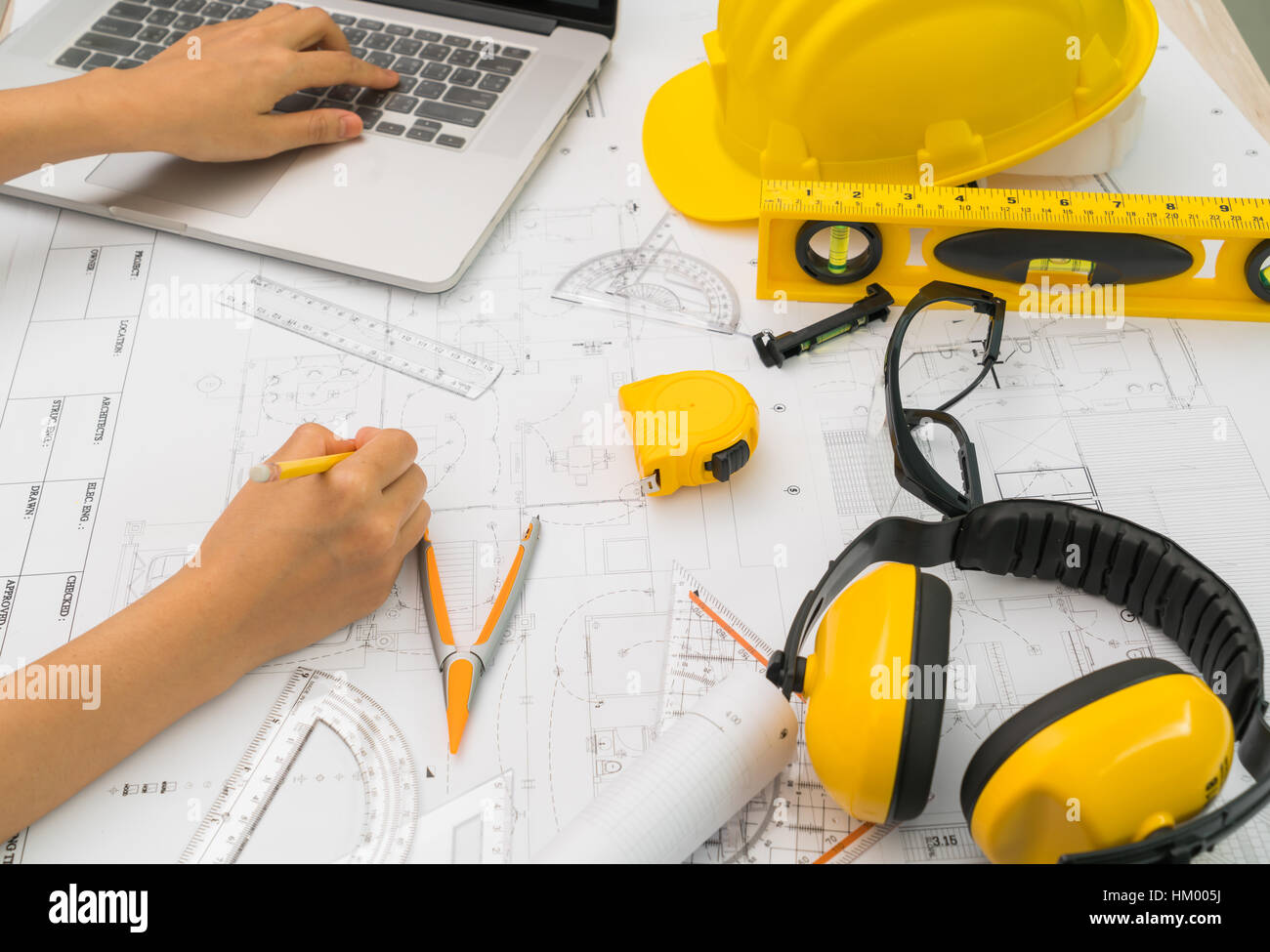Hand over Construction plans with yellow helmet and drawing tools on ...