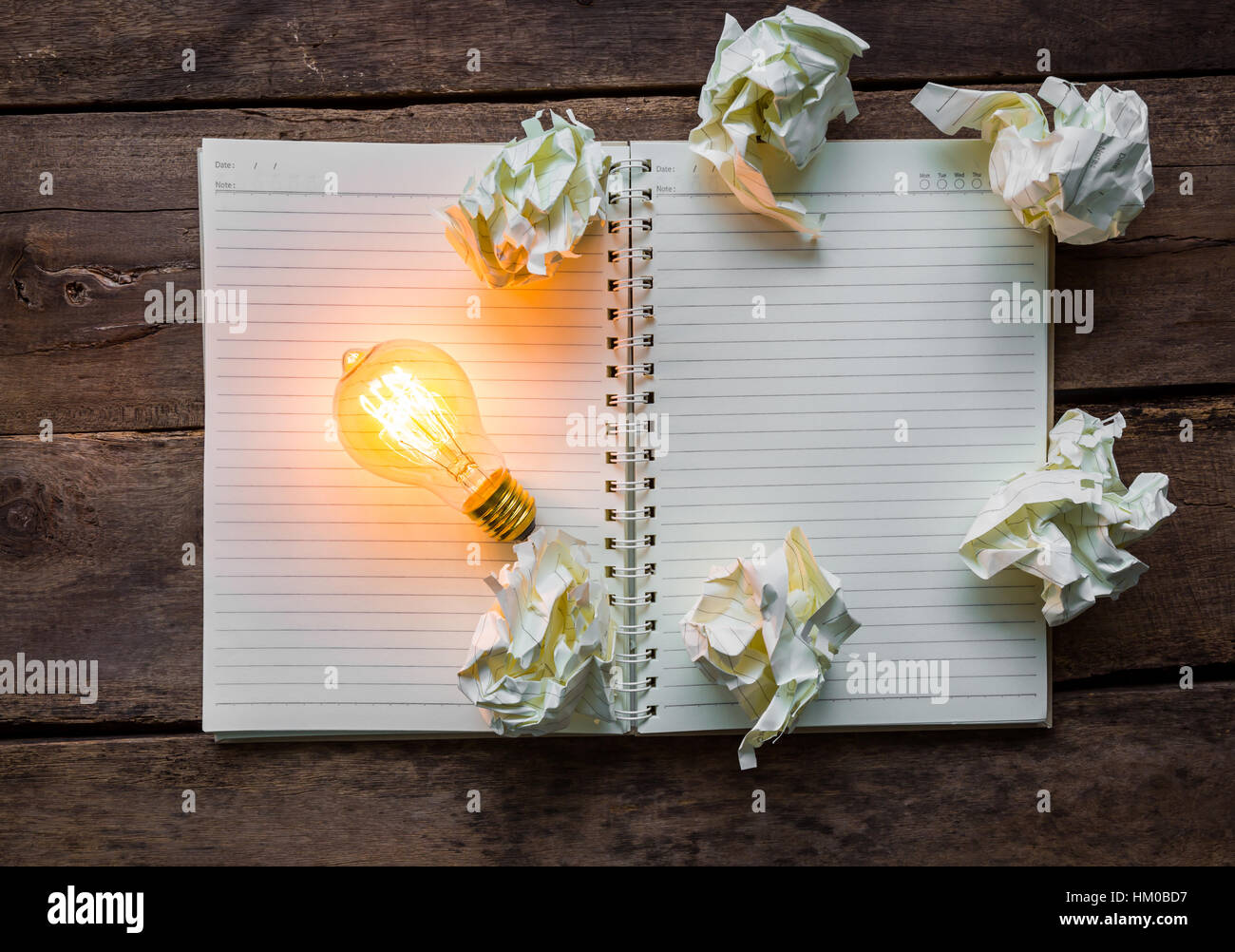 Note book and light bulb on wood table Stock Photo - Alamy