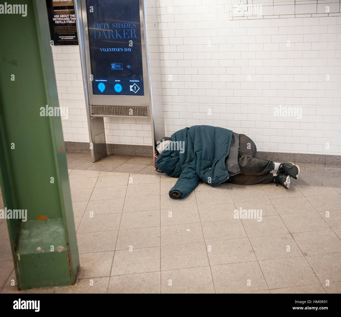 A homeless individual sleeps in a subway station in New York on ...