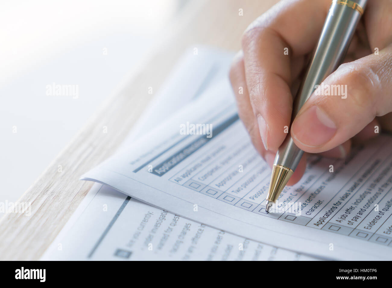 Hand with pen over application form Stock Photo - Alamy