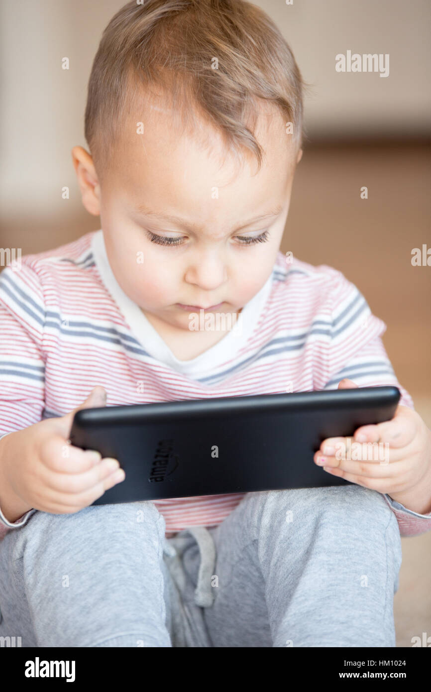 Little toddler boy holding and playing on a computer tablet Stock Photo ...