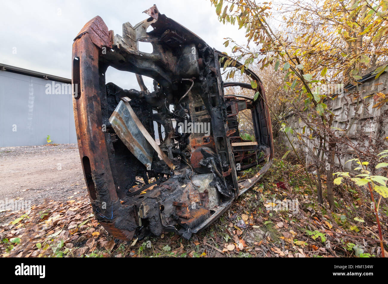Rusty burned-out SUV on its side. Near the concrete fence on the ...