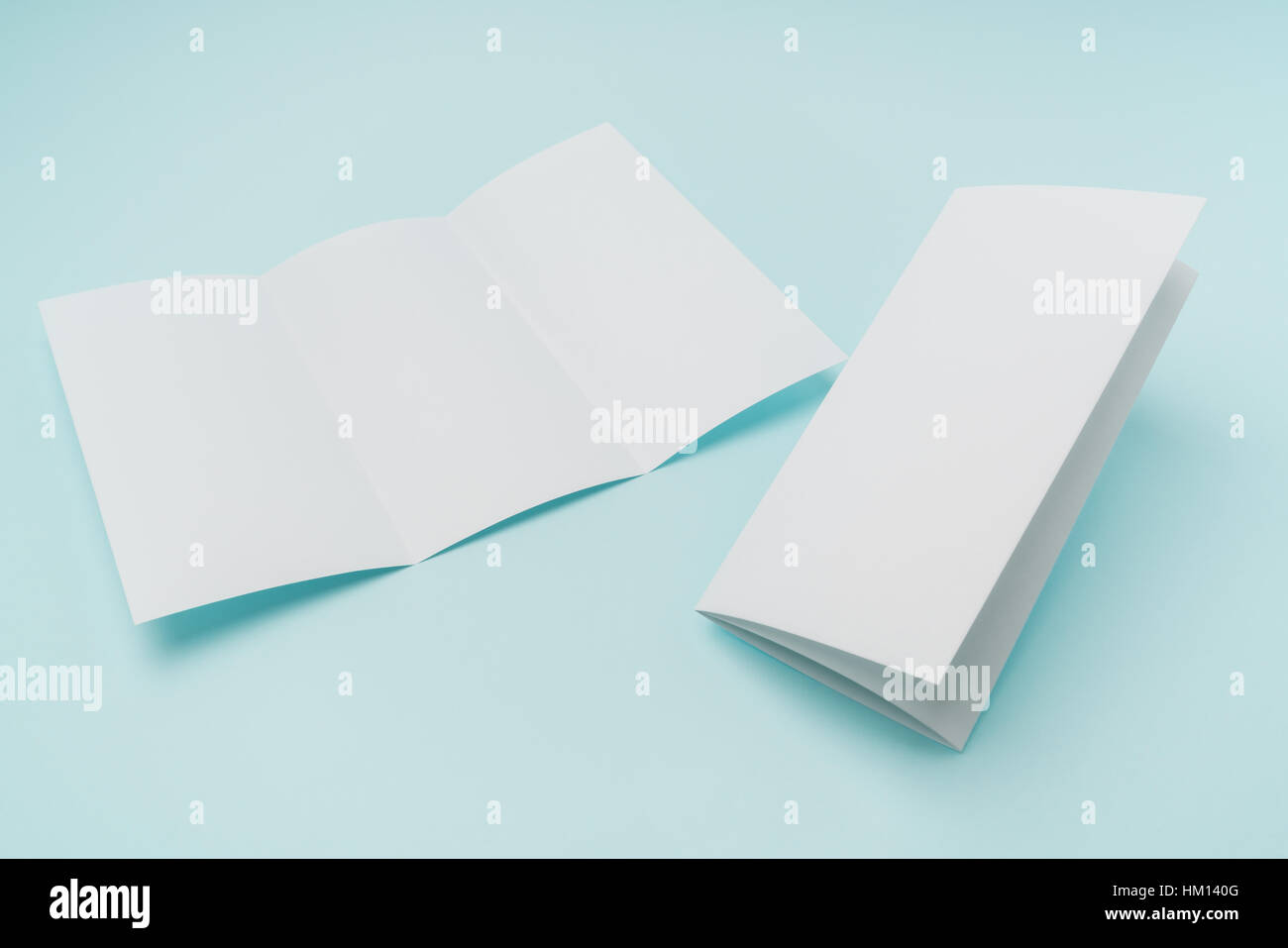 Trifold white template paper on blue background Stock Photo - Alamy