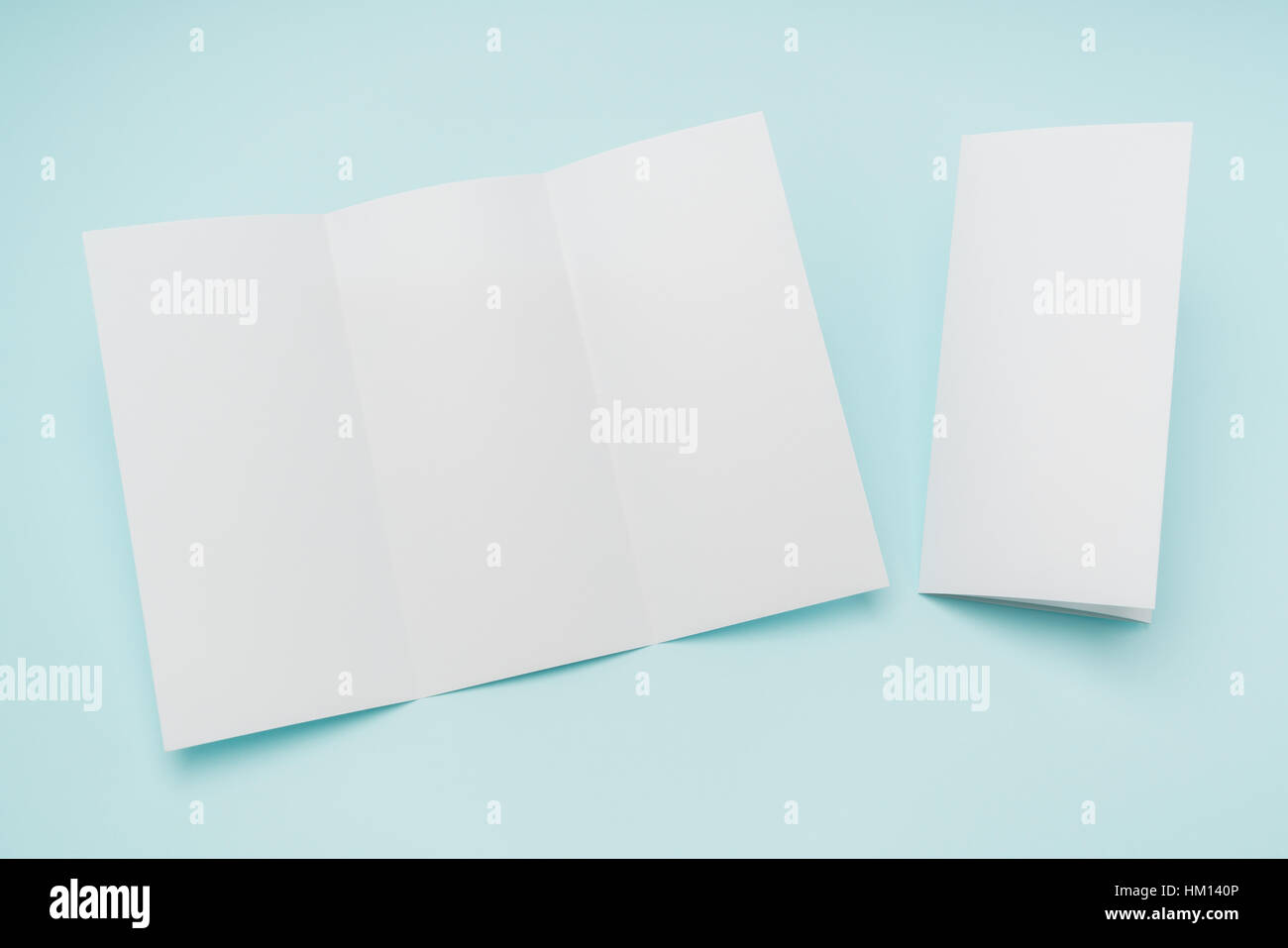 Trifold white template paper on blue background Stock Photo - Alamy