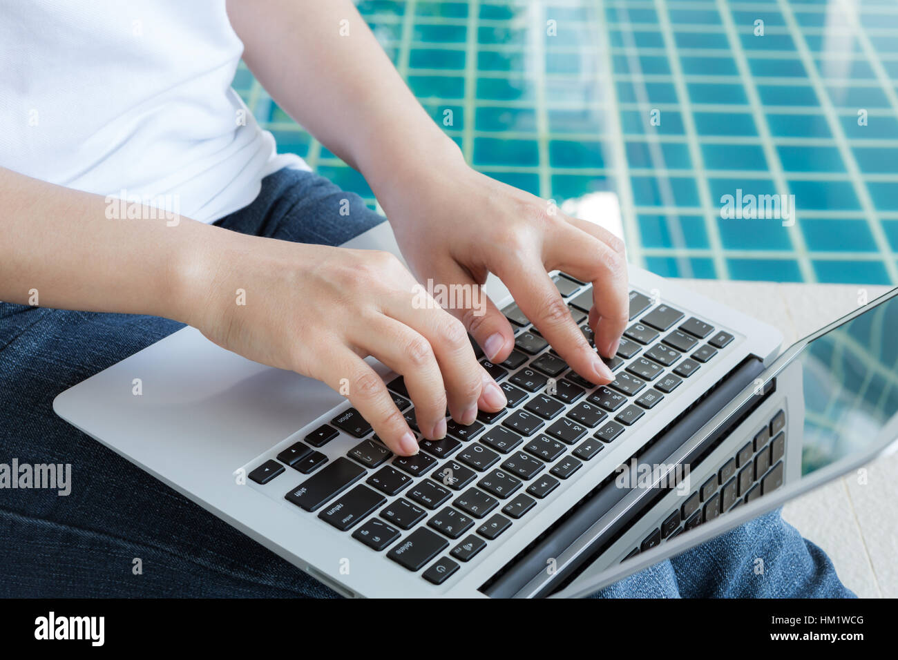 Woman working with laptop computer sitting at swimming pool Stock Photo ...