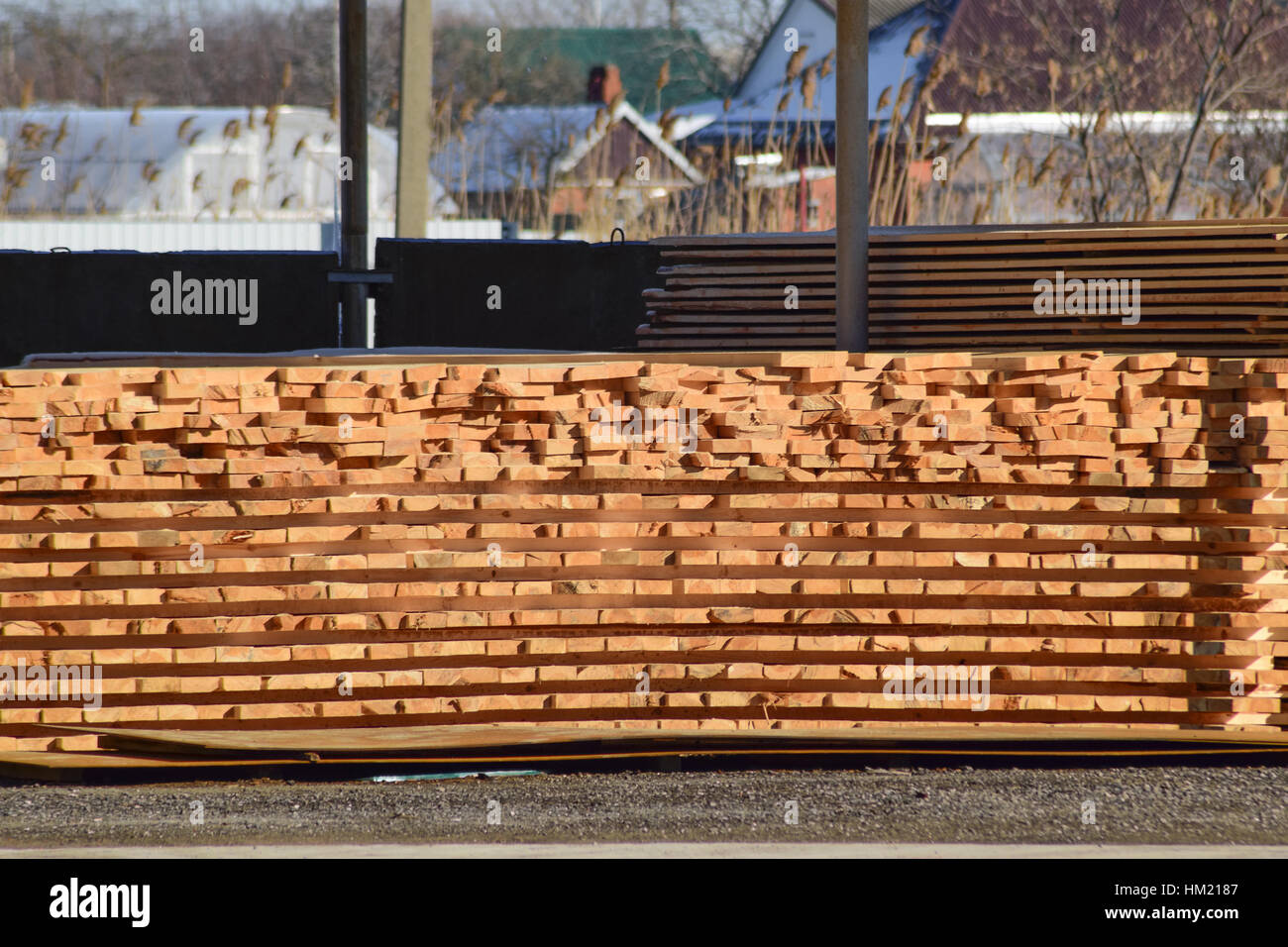 Warehouse of building materials, wood planks stacked under a canopy ...