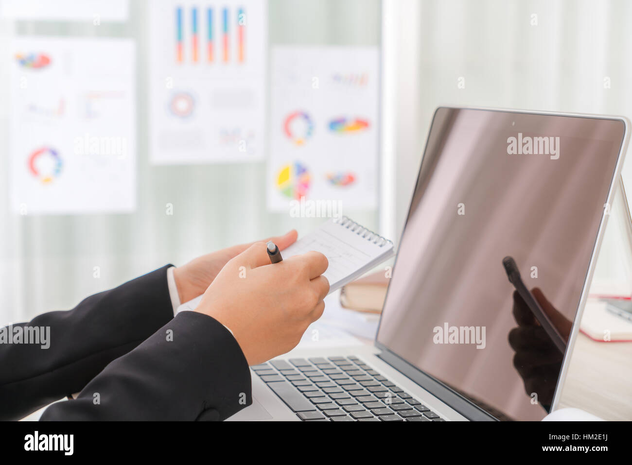 Business people using a pencil noting over laptop Stock Photo - Alamy